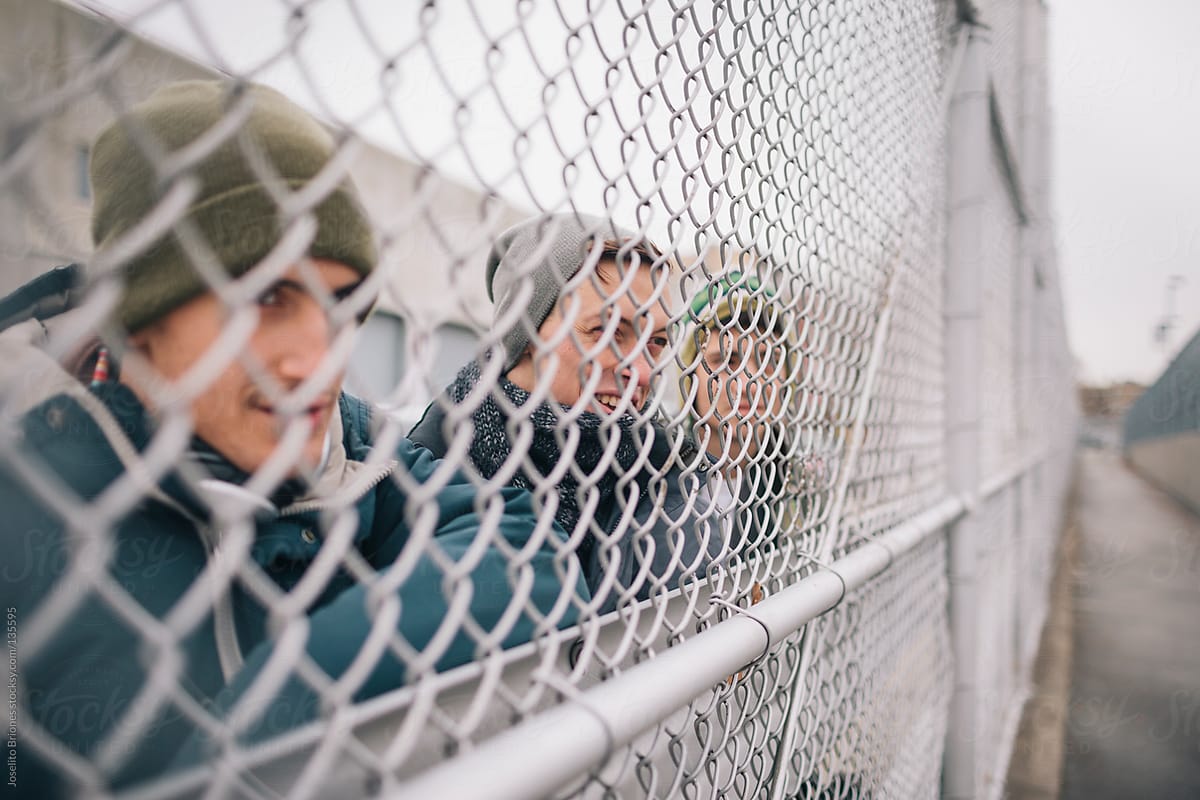"Group Of Young Men Friends Watching Through Chainlink Fence" by ...