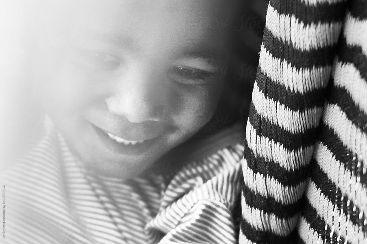 "Smiling Boy Hiding" by Stocksy Contributor "PER Images" - Stocksy