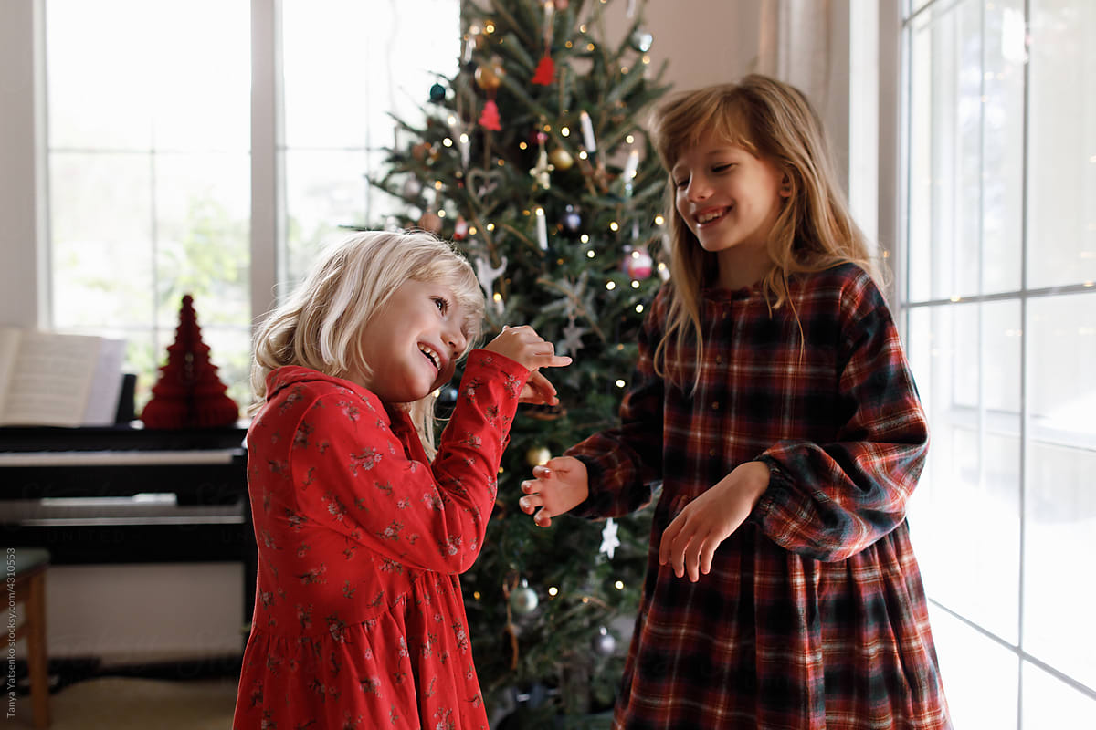Two sisters near a Christmas tree - Stock Image - Everypixel