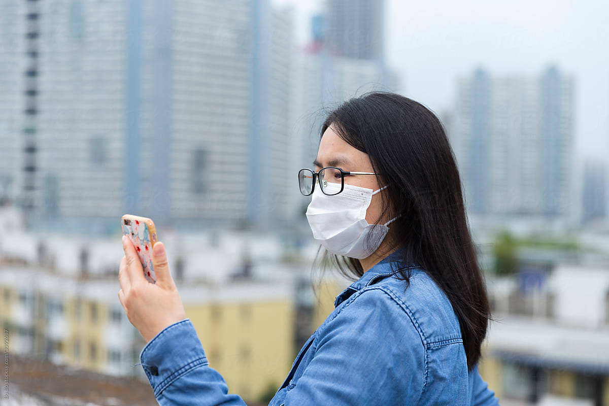 "Asian Woman Wear Mask Standing On The Roof" by Stocksy Contributor "Bo ...