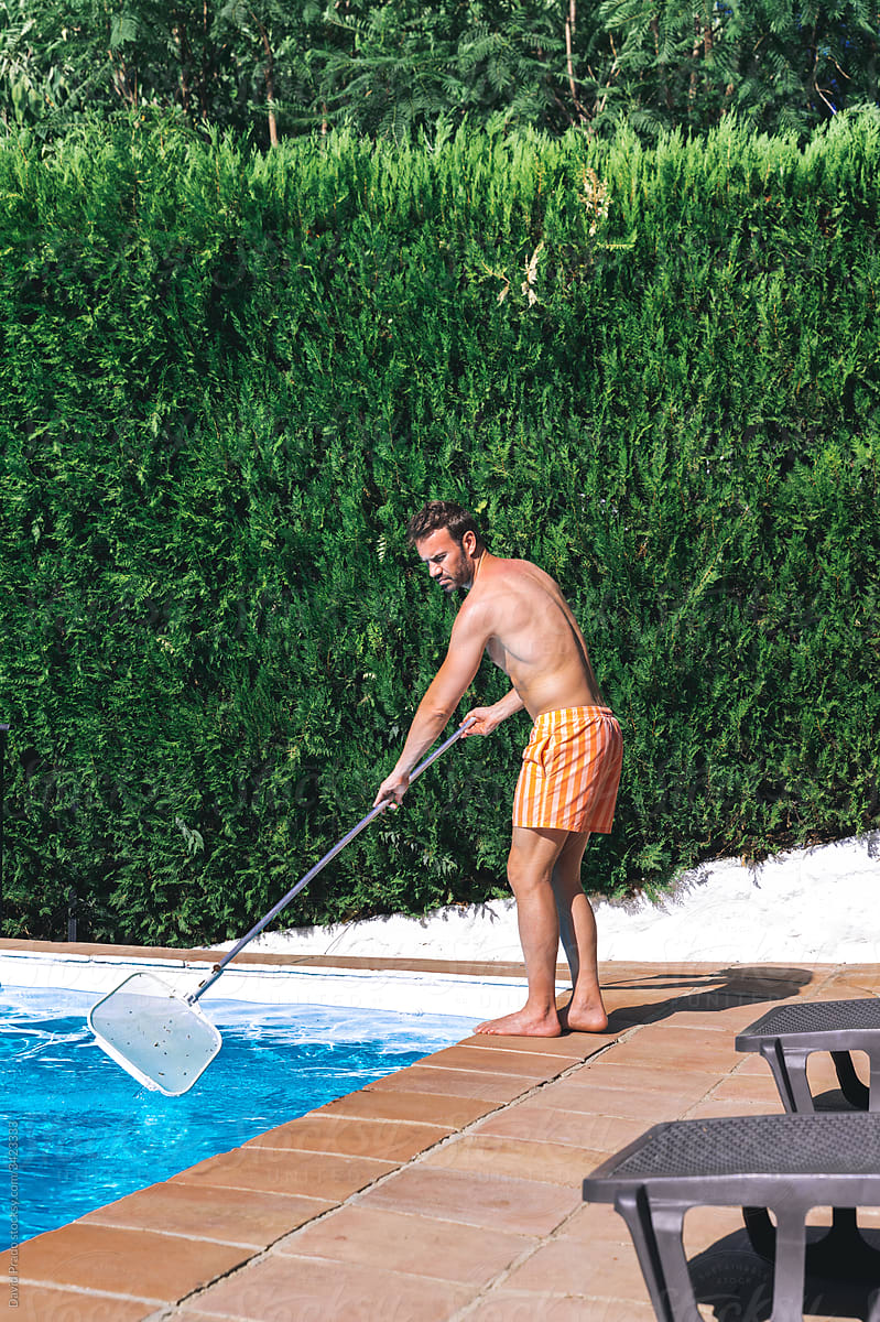"Man Cleaning Pool With Net" by Stocksy Contributor "David Prado" - Stocksy