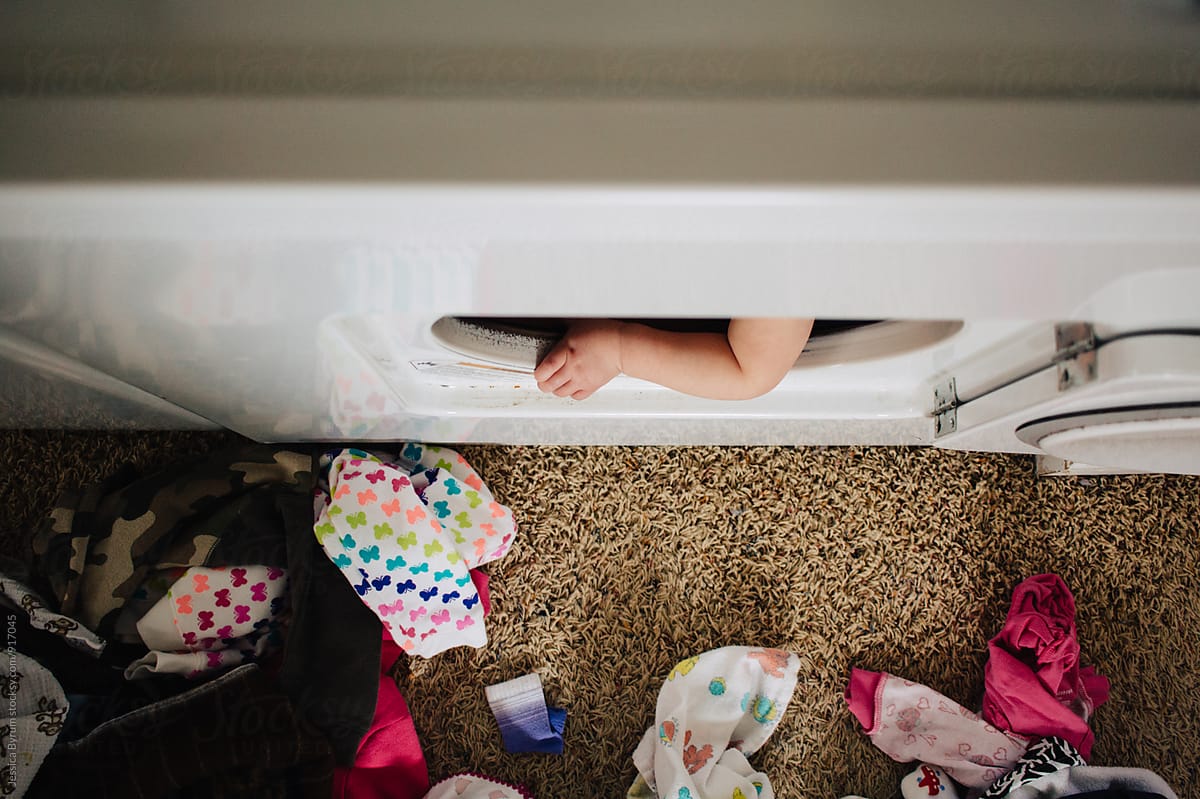 "Toddler Hiding In Dryer" by Stocksy Contributor "Jessica Byrum" - Stocksy