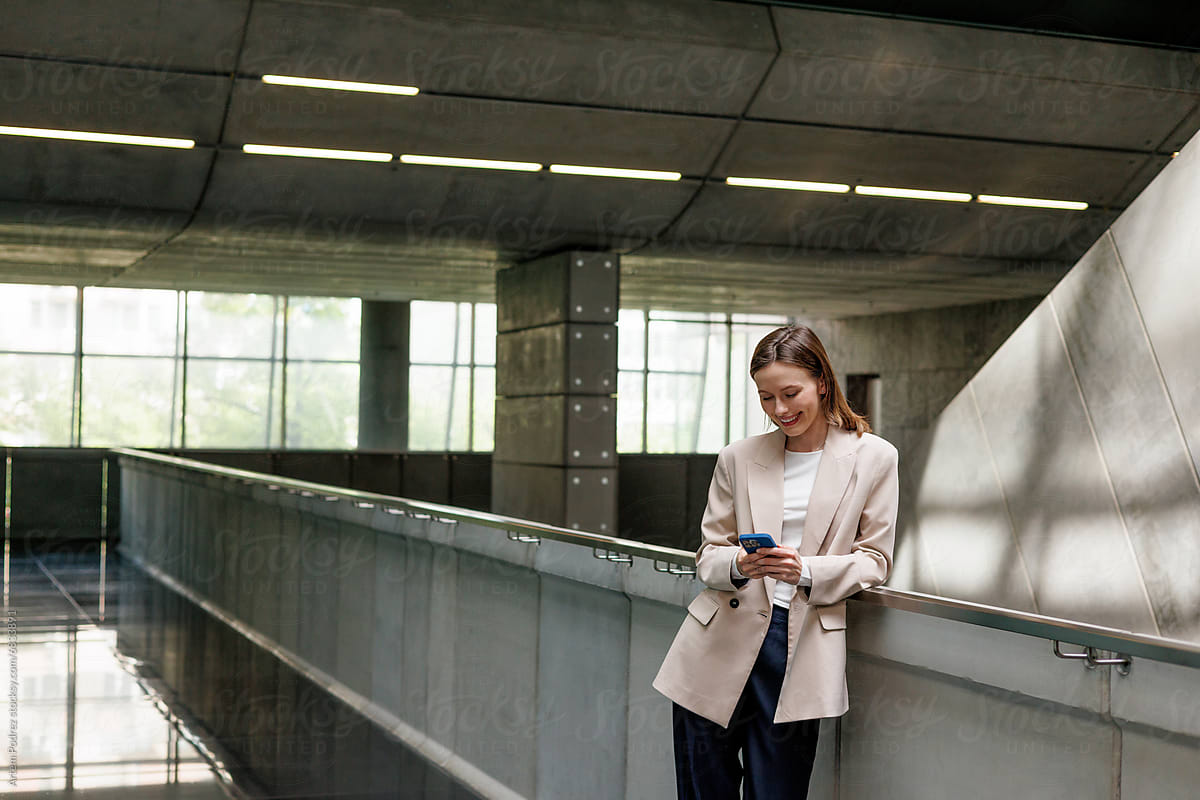 "Stylish Woman Using Phone In Glass Hallway" by Stocksy Contributor ...