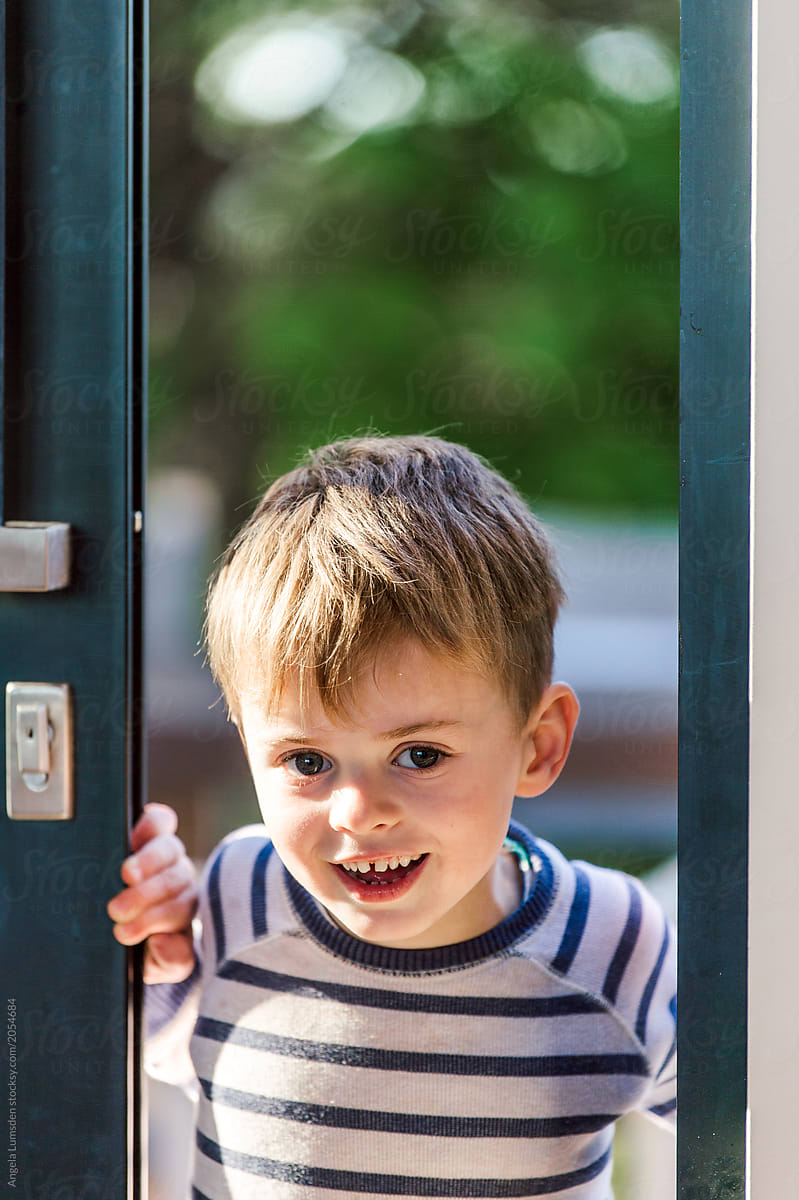 Smiling Boy Looking Through An Open Door From Outside By Stocksy Smiling Boy Looking Through An Open Door From Outside By Stocksy