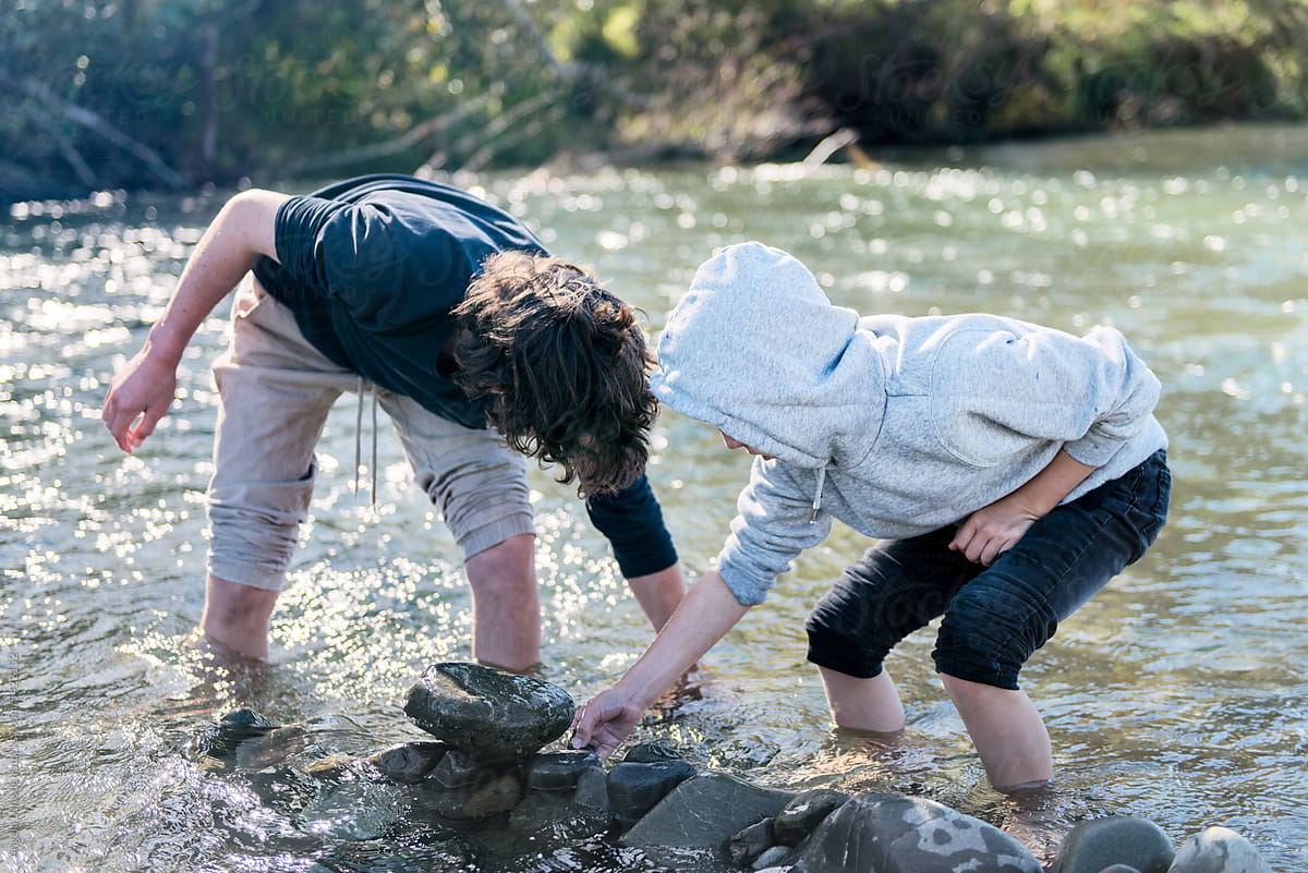 "Older Boy Helping Younger Cousin To Build A Dam" by Stocksy ...