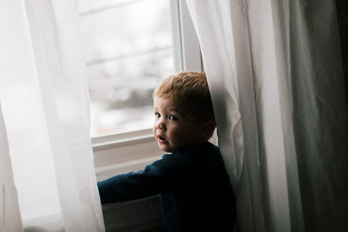 "Child Standing In Window Surrounded By Curtains" by Stocksy ...