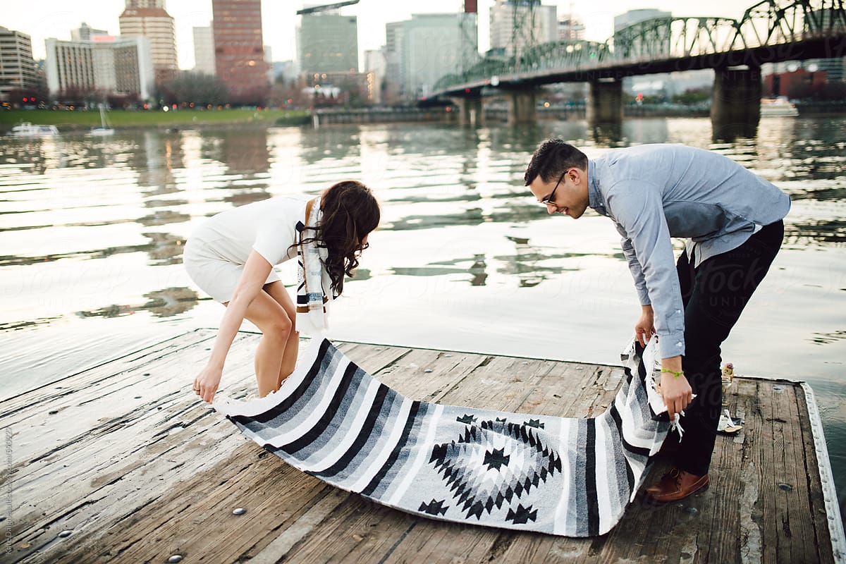 "Young Couple Spreading A Blanket On A Dock At The City Waterfront" by ...