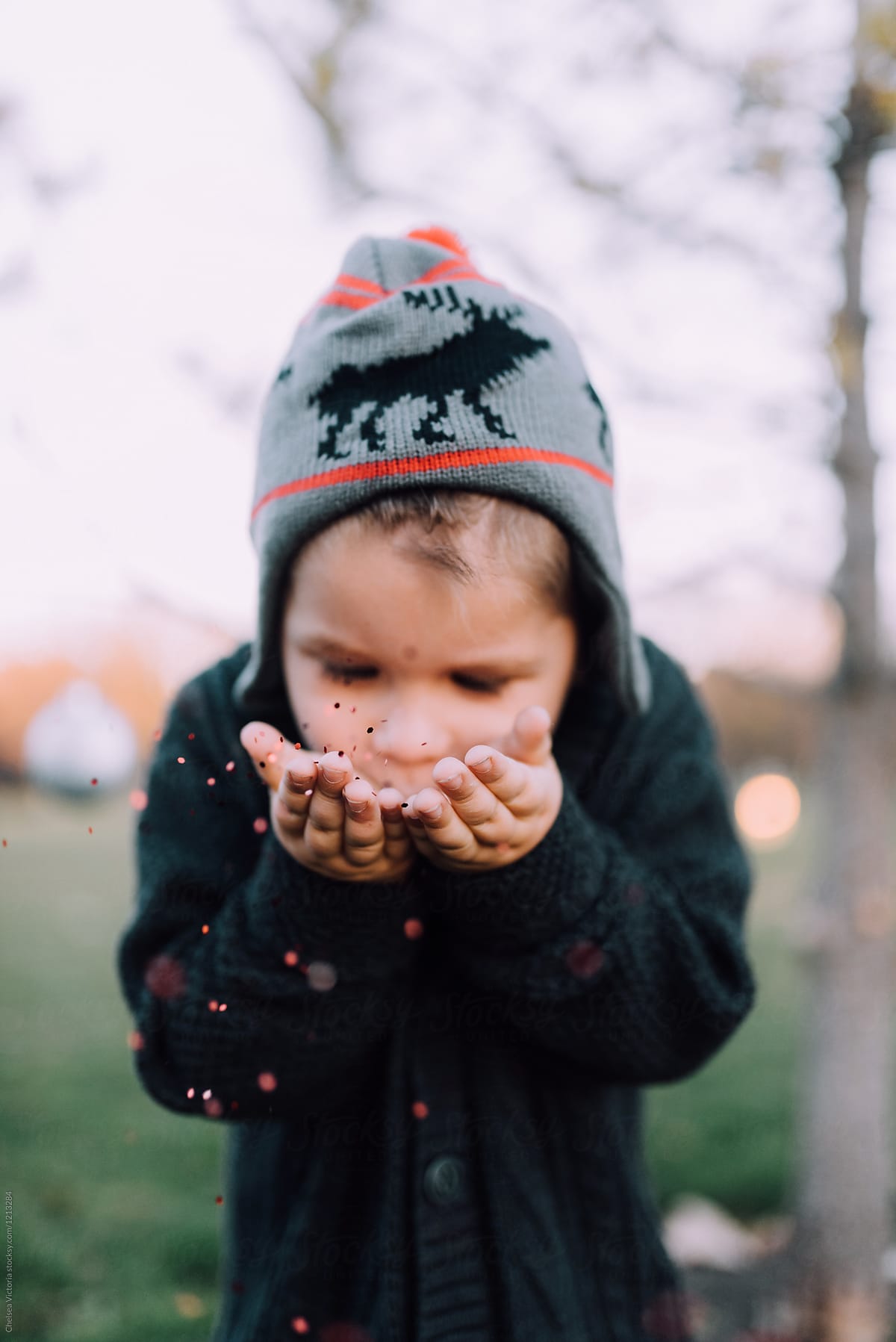 "A Young Boy Blowing Christmas Glitter While Wearing A Santa Hat" by ...