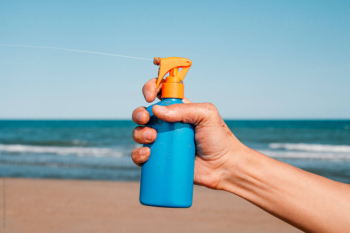 "Man Spraying Some Sun Cream On The Beach" by Stocksy Contributor "Juan ...