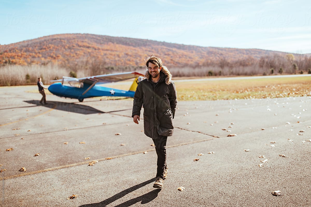 "Smiling Man Walking From His Glider Flight On An Airfield" by Stocksy ...