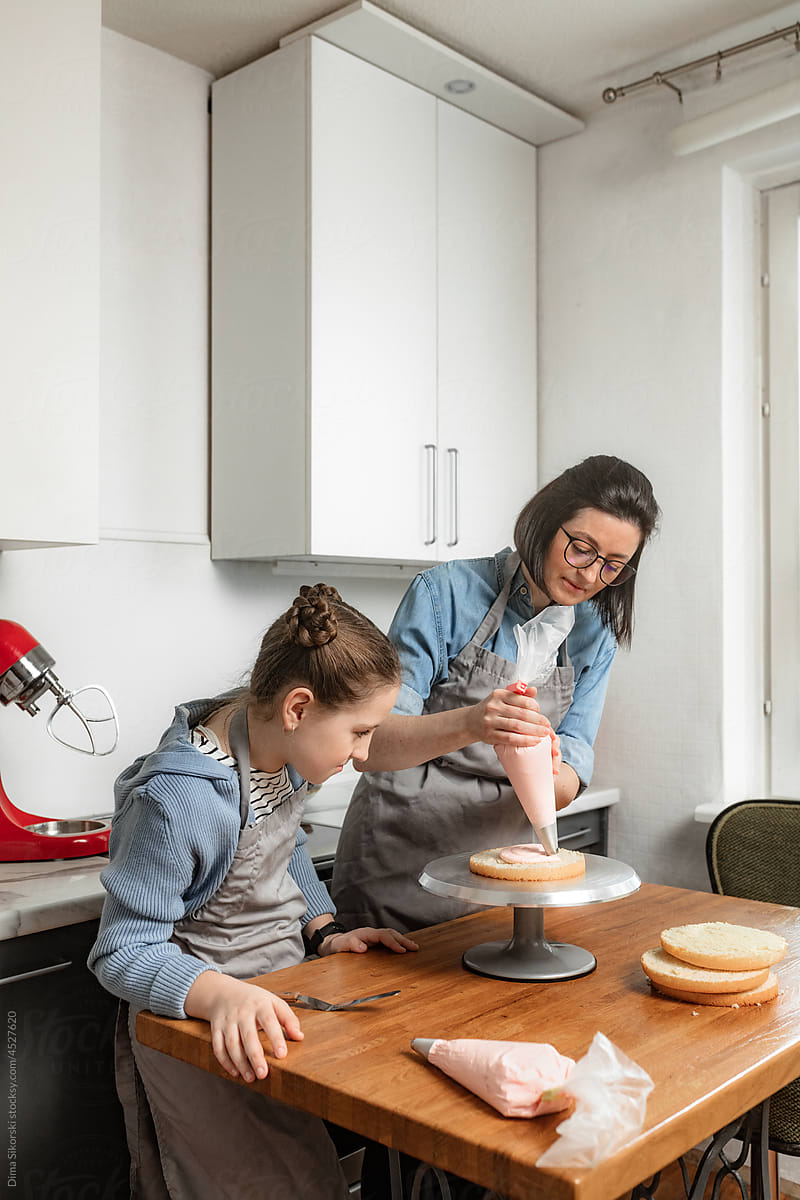 Mother teaches daughter to cook cake in the kitchen together - Stock ...
