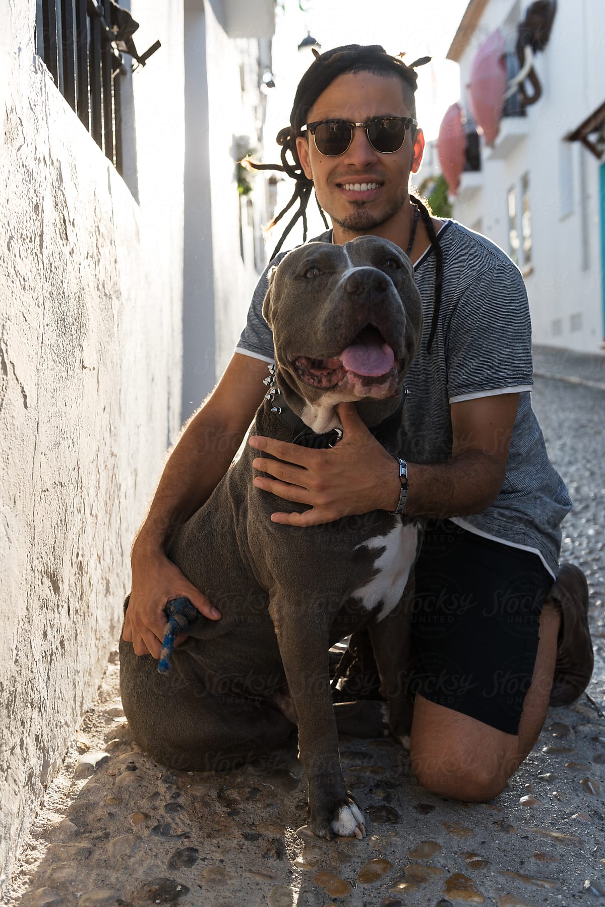 "Cheerful Man Embracing Dog In Street" by Stocksy Contributor "Milles ...