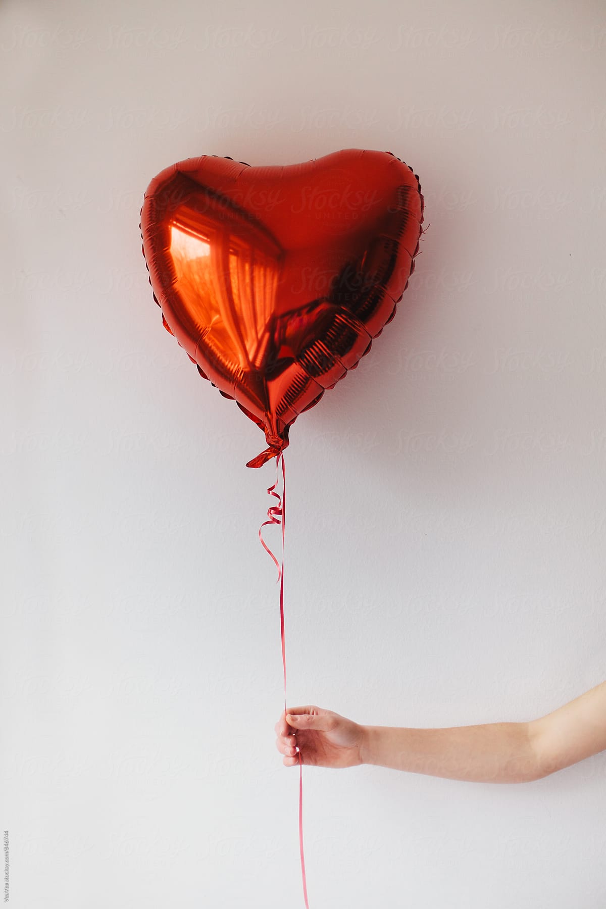 "Hand Holding A Red Heart Ballon In Front Of A White Wall" by Stocksy ...