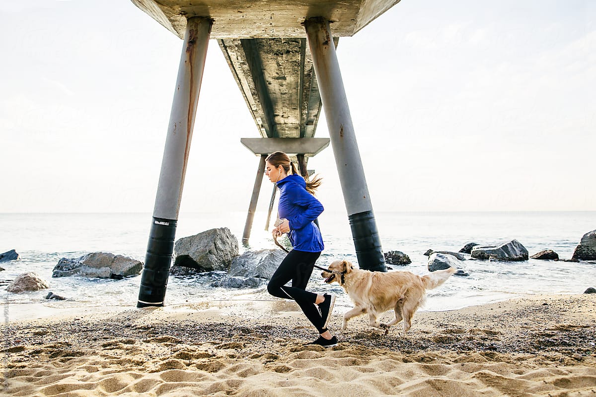 "Side View Of A Woman Running With Her Dog On The Beach." by Stocksy ...