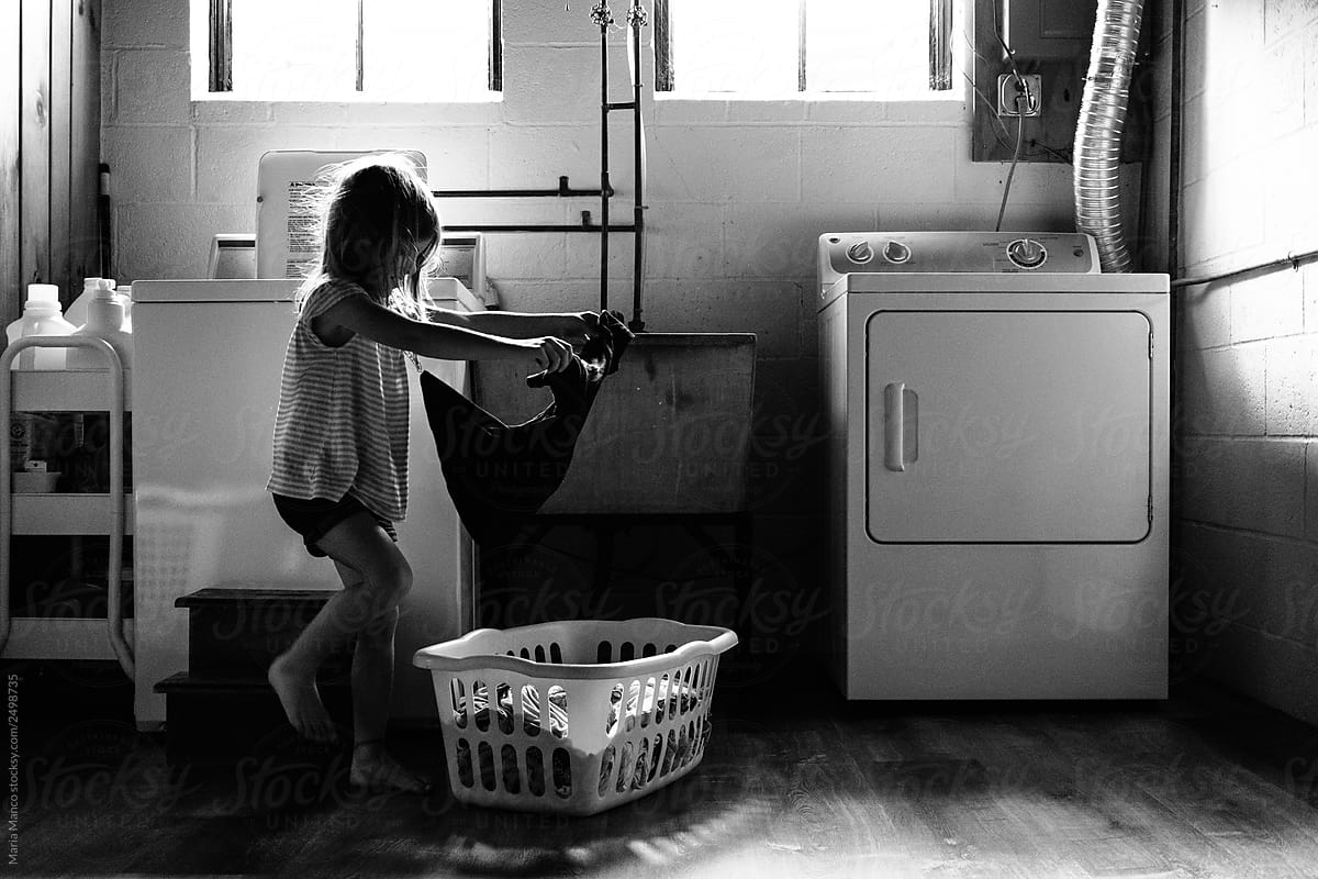 "Little Girl Does Laundry" by Stocksy Contributor "Maria Manco" - Stocksy