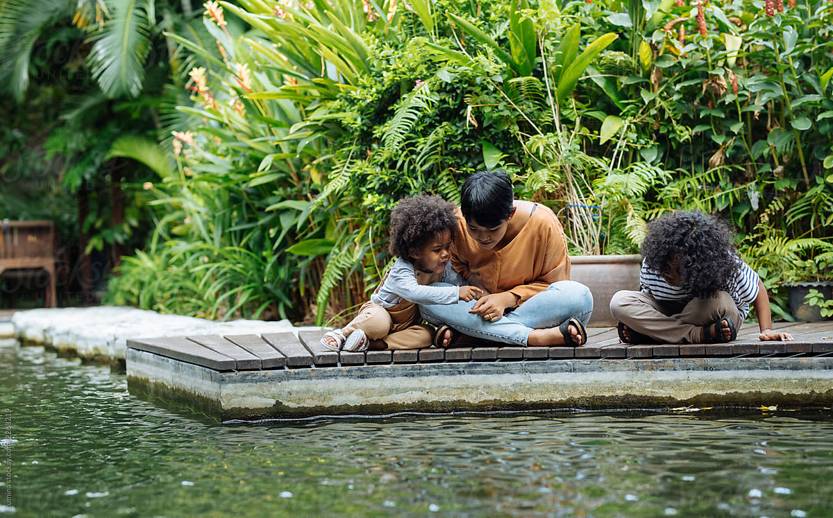 "Family Enjoying Sitting By The Lake At Park" by Stocksy Contributor ...