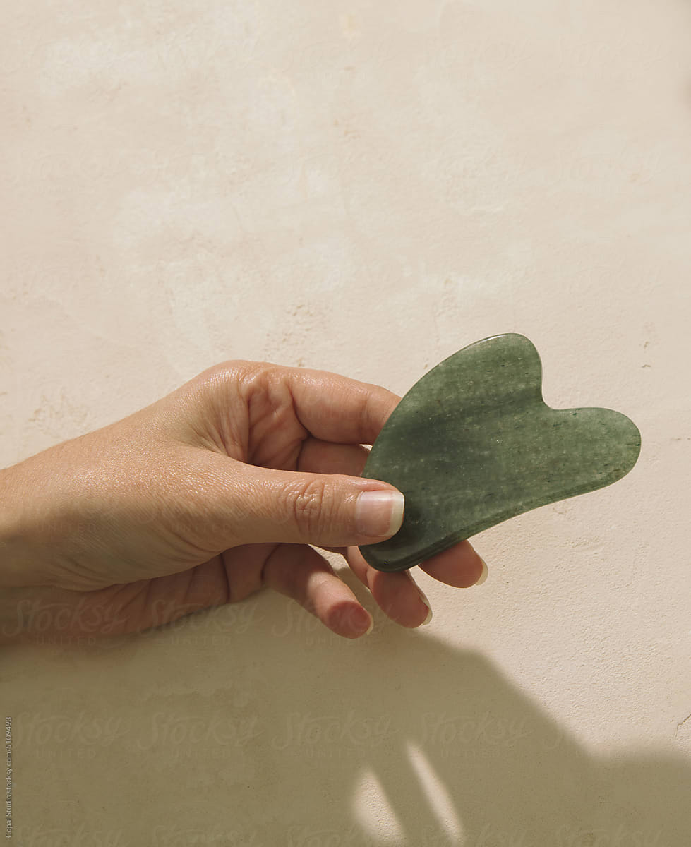 "Hand Holding Gua Sha Over Tan Plaster Wall With Natural Lighting" by ...