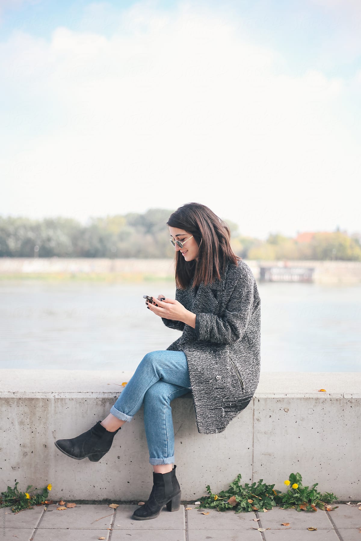 "Stylish Woman Browsing On Her Mobile Phone Sitting On A Quay" by ...