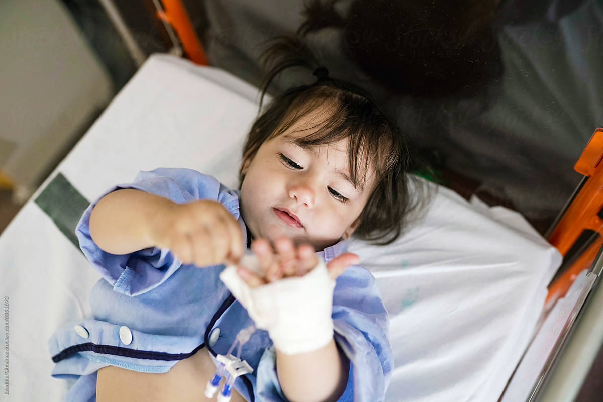 "Sick Toddler Girl Lying In Hospital Bed Playing With Bandage On Hand ...