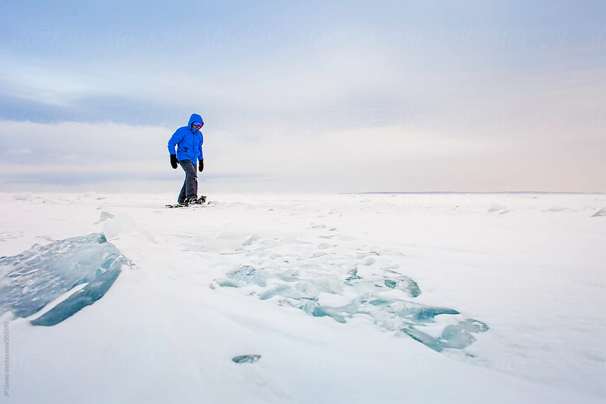"Man On Snow Shoes Walking Into Wind Across Frozen Lake Ice In Winter ...