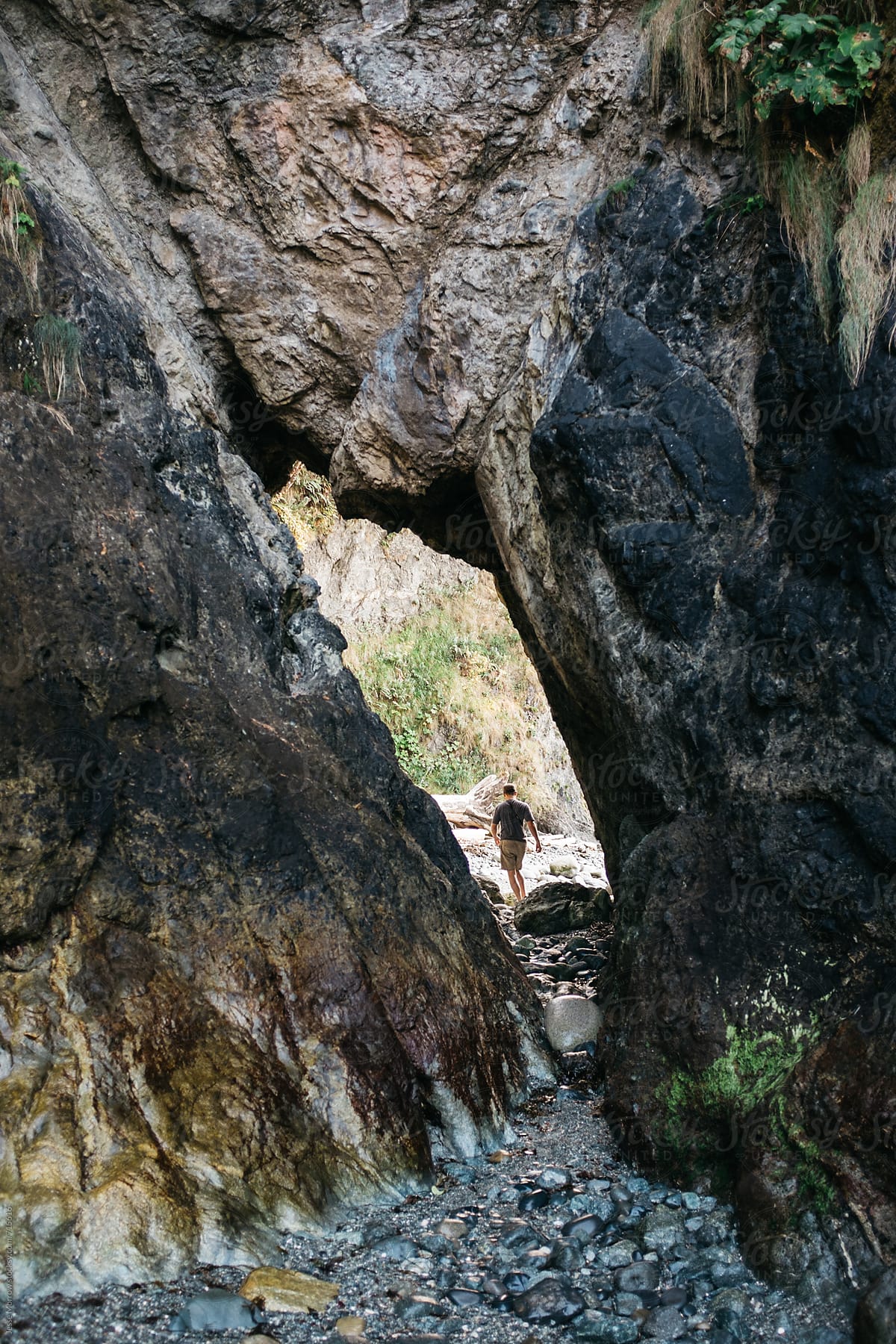 "Young Man Walks Through Arch On Beach" by Stocksy Contributor "Jesse ...