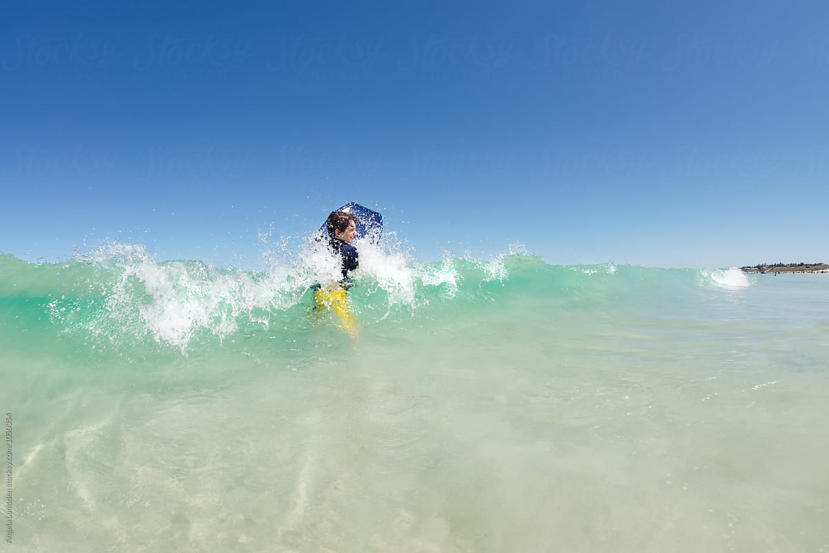 "Boy With A Boogie Board Splashes Through A Low Wave At The Beach In ...