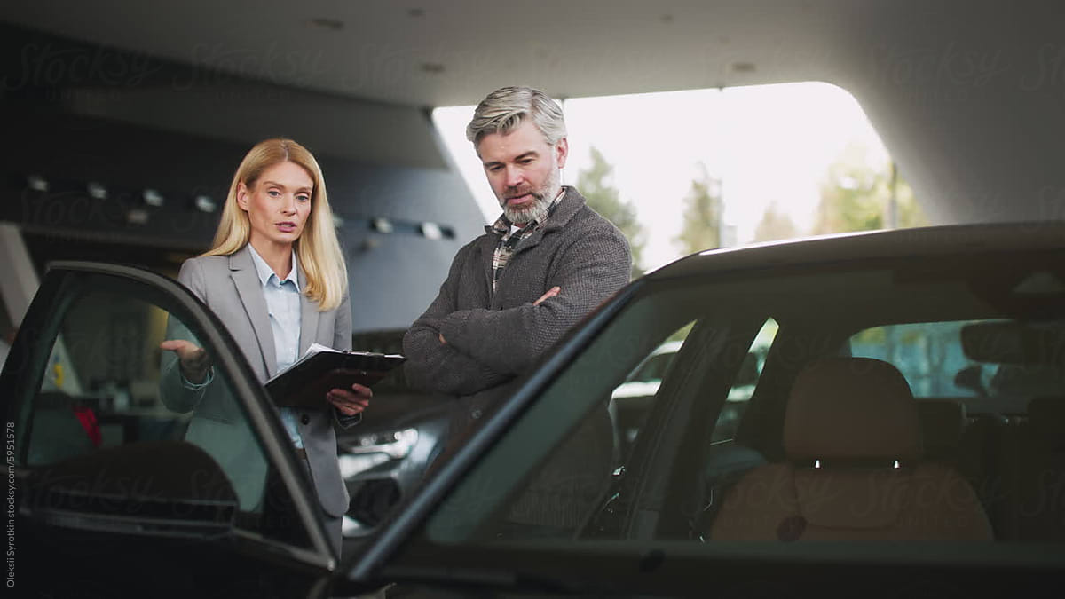 "Agent Reading Out Automotive Specifications To Customer In Showroom ...