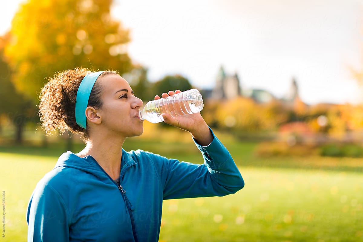 "Young Woman Drinking From Water Bottle While Jogging In Ottawa In ...