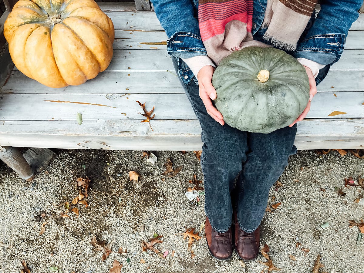 "Seated Woman Holding Green Pumpkin On Wooden Bench Next To Orange ...