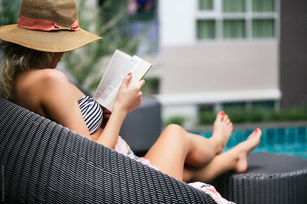 "Woman Reads A Book By A Pool" by Stocksy Contributor "Lumina" - Stocksy