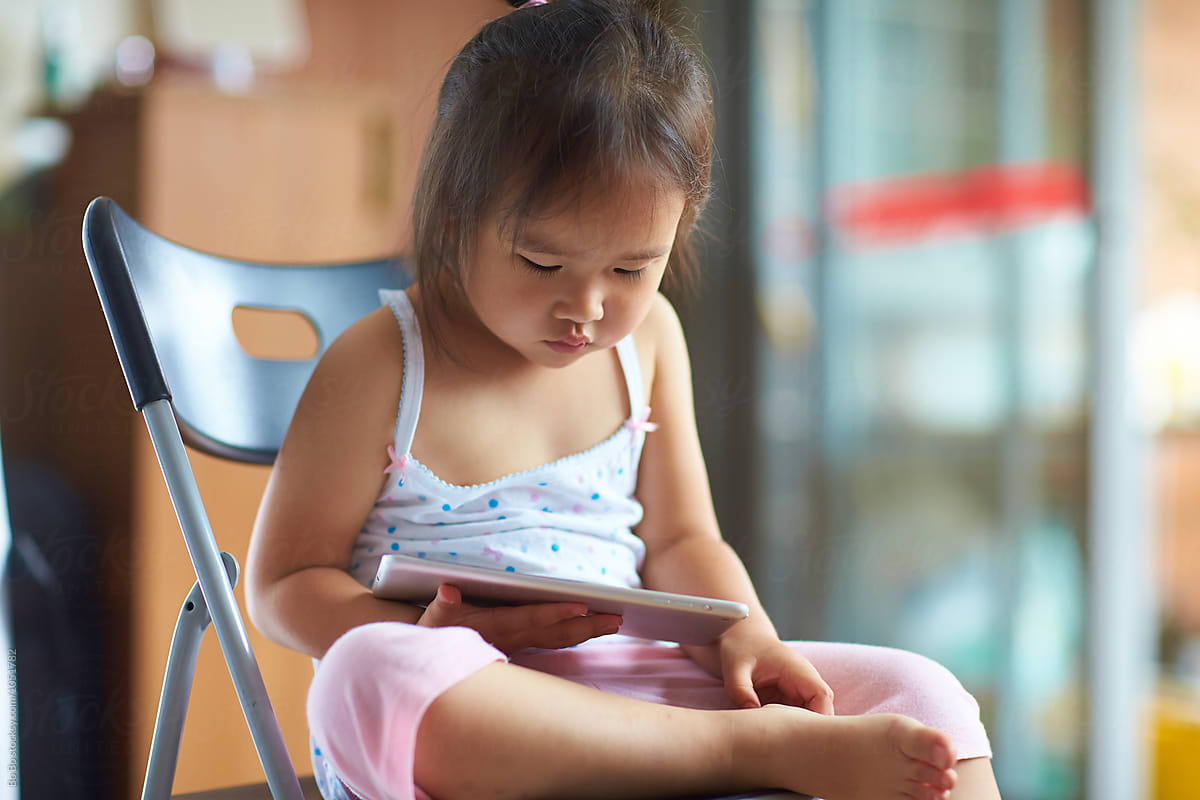 "Little Girl Using Tablet Indoor" by Stocksy Contributor "Bo Bo" - Stocksy
