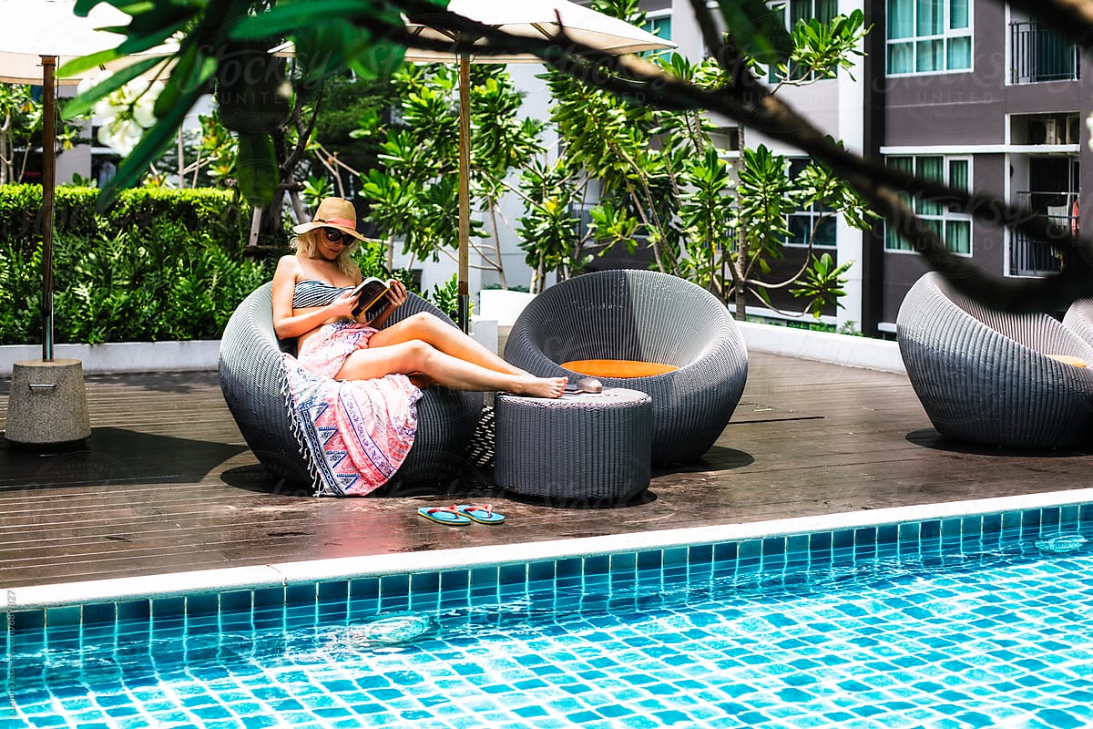 "Woman Reads A Book By A Pool" by Stocksy Contributor "Lumina" - Stocksy