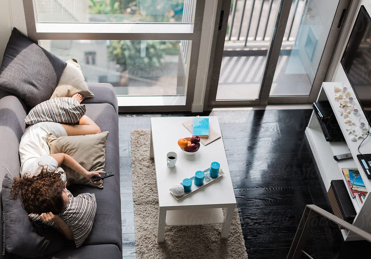 "Young Woman Watching TV At Home" by Stocksy Contributor "Mosuno" - Stocksy