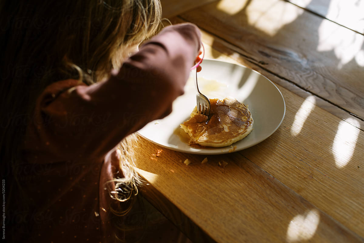 "Little Girl In Pajamas Eating Pancake For Breakfast At Kitchen Table ...