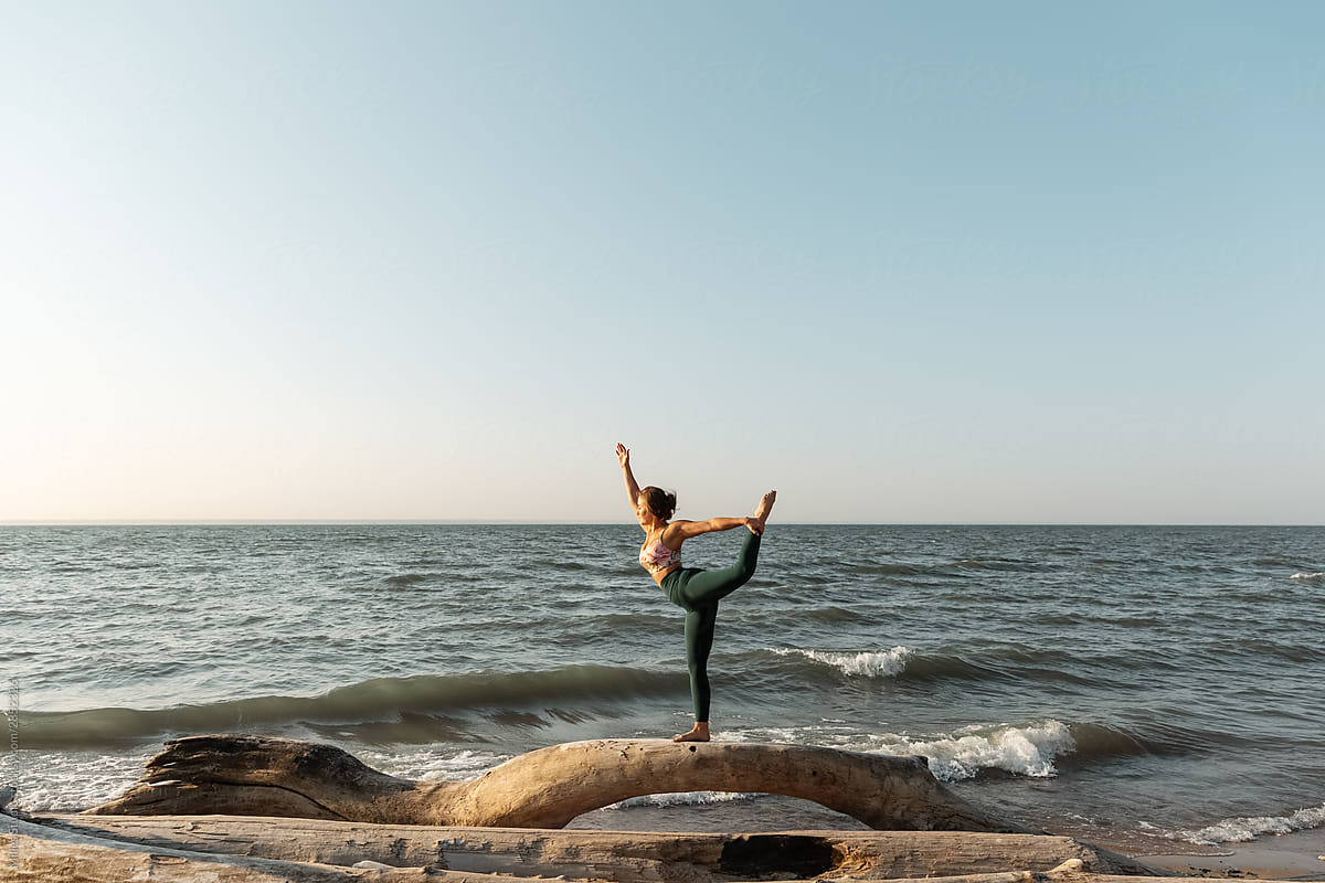 "Solitary Fit Woman Practicing Yoga In Balance Pose On Ocean Beach" by ...