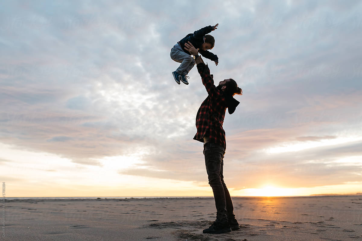 "Man Lifting Son Up On Shoreline" by Stocksy Contributor "Guille ...