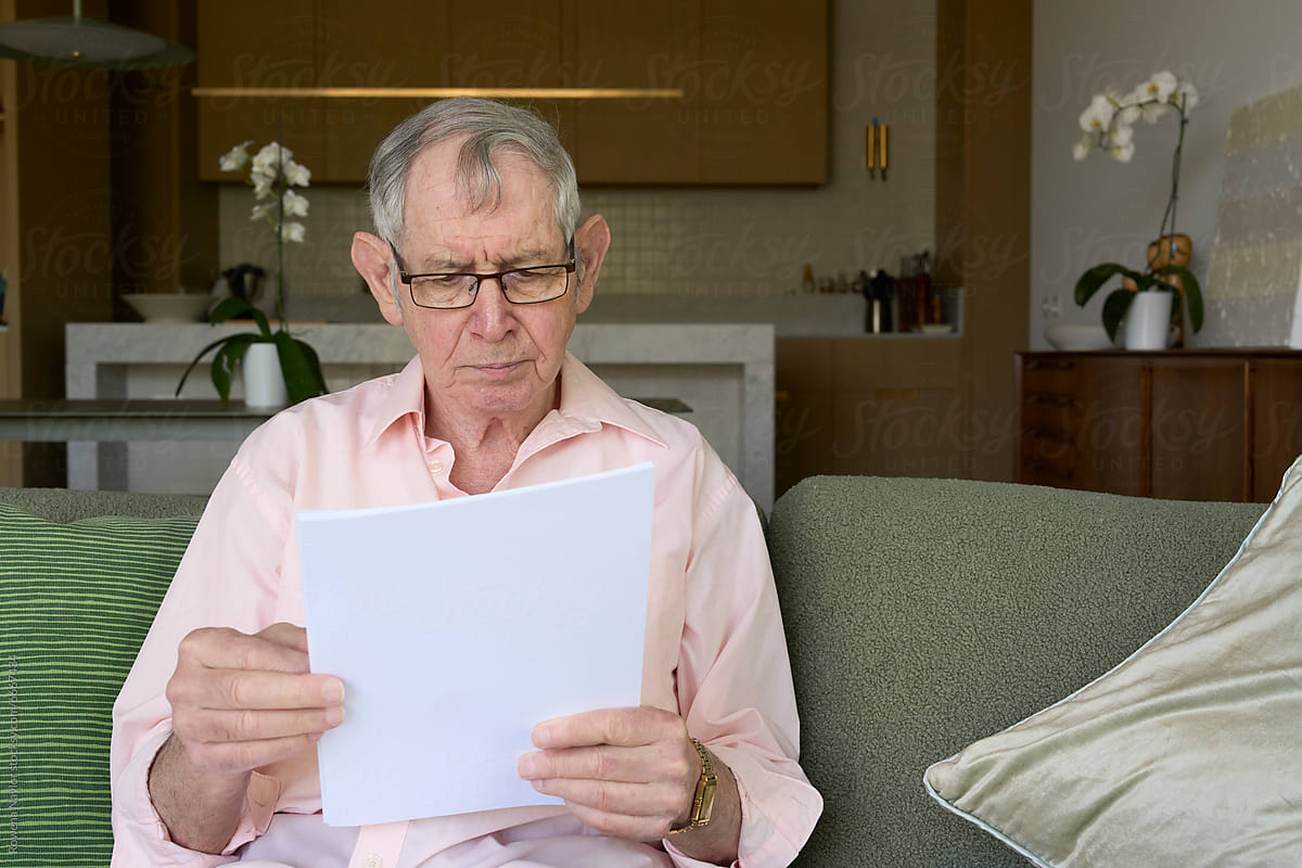"Older Man Reading Documents In A Modern Living Room" by Stocksy ...