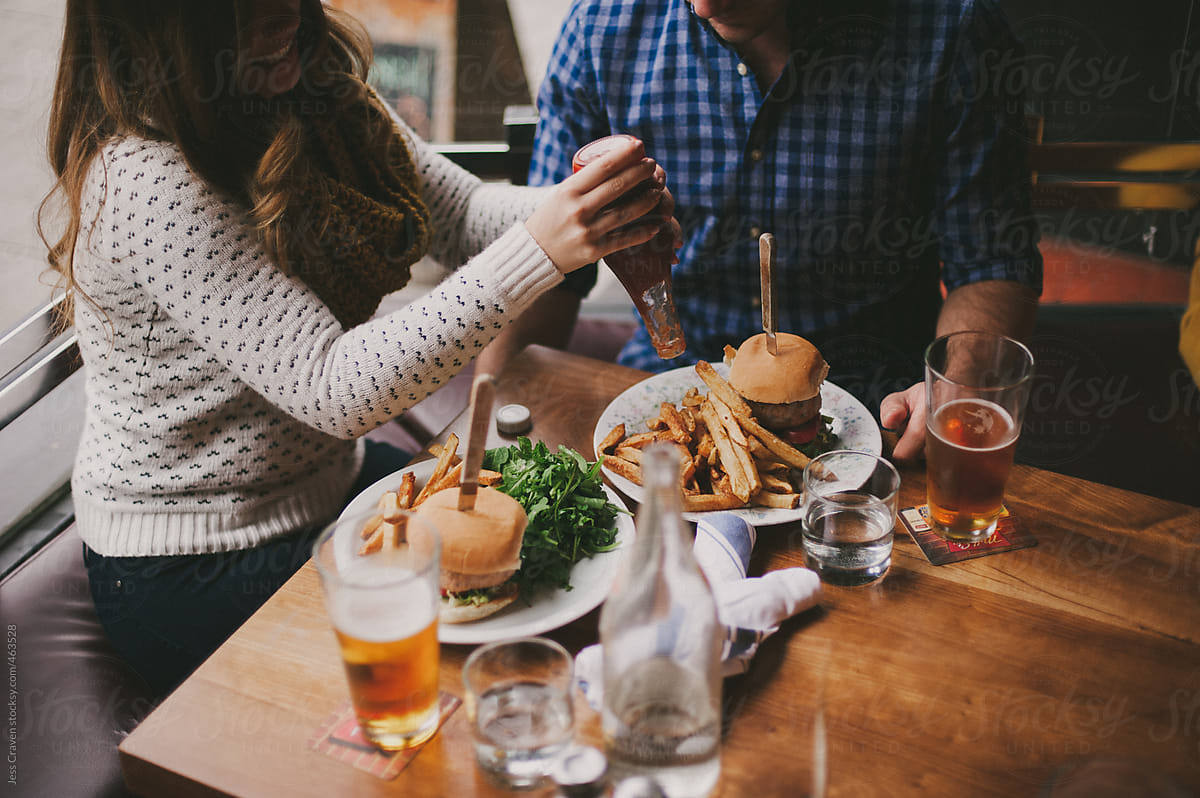 "Couple On Date Eating Burgers And Fries" by Stocksy Contributor "Jess ...
