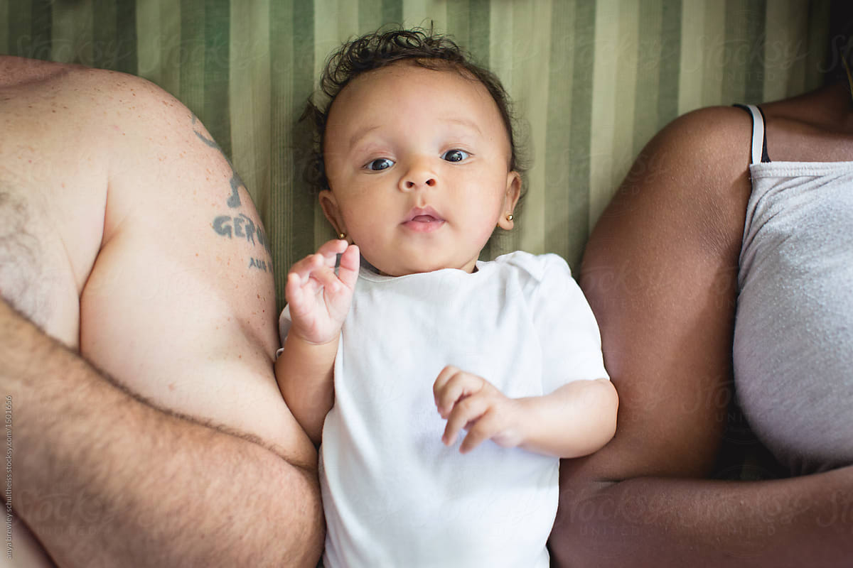 Biracial Baby Lying In Bed Between Her Black Mother And White Father Biracial Baby Lying In Bed Between Her Black Mother And White Father