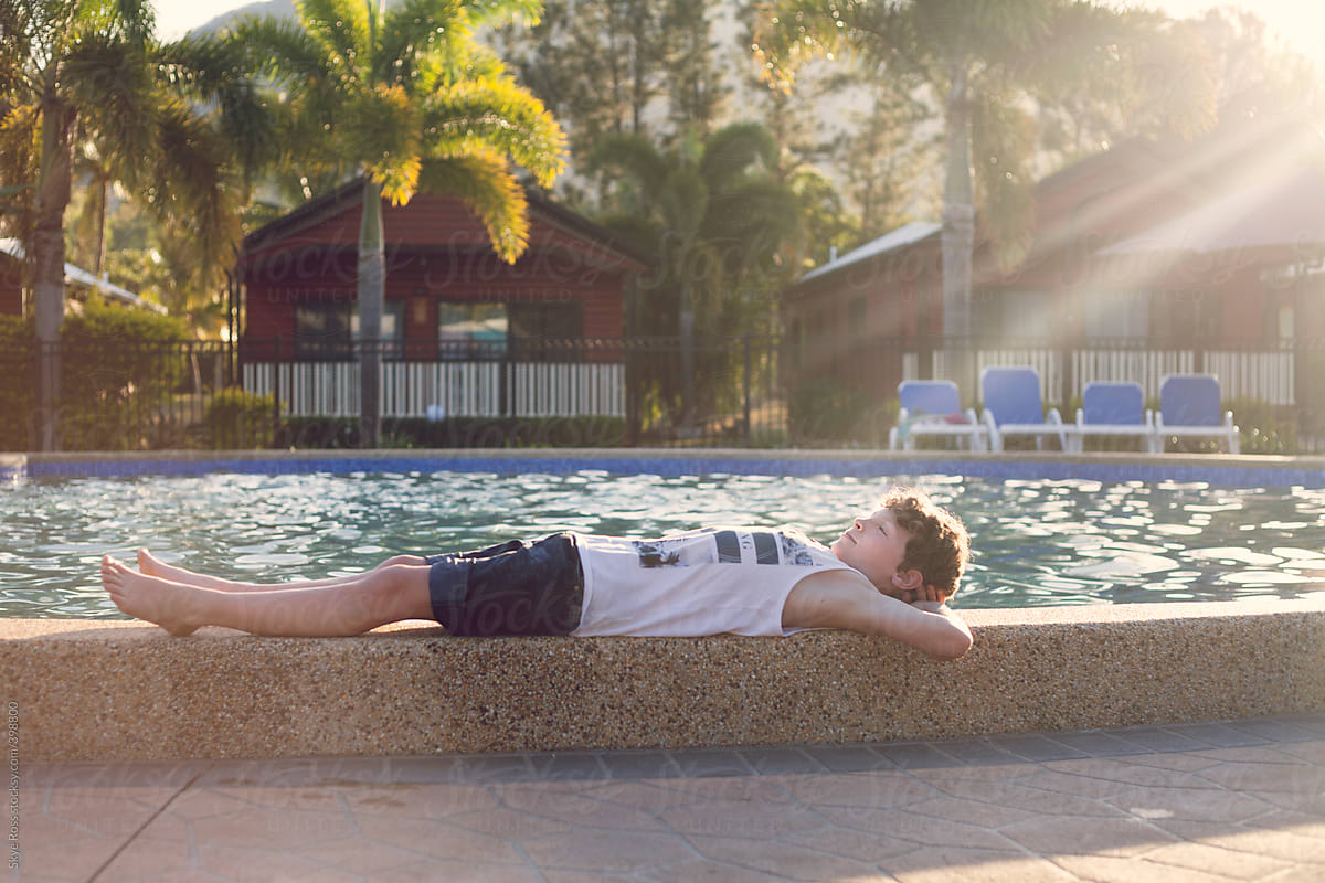 "Boy Relaxing On Pool Edge." by Stocksy Contributor "Skye Ross" - Stocksy