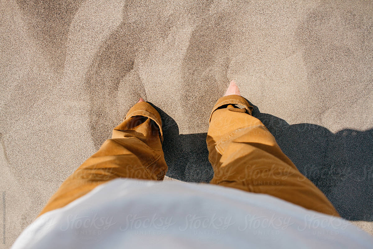 "Man Looking Down At Feet Buried In Sand" by Stocksy Contributor "Jesse ...