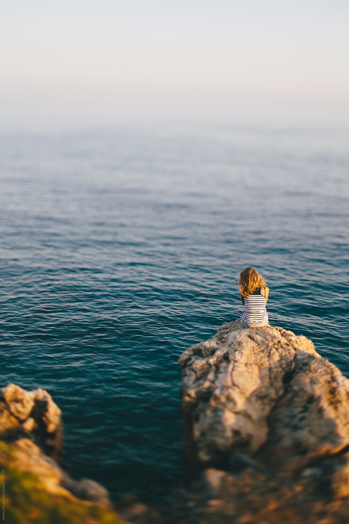 "Woman Sitting On A Rock" by Stocksy Contributor "Andrey Pavlov" - Stocksy