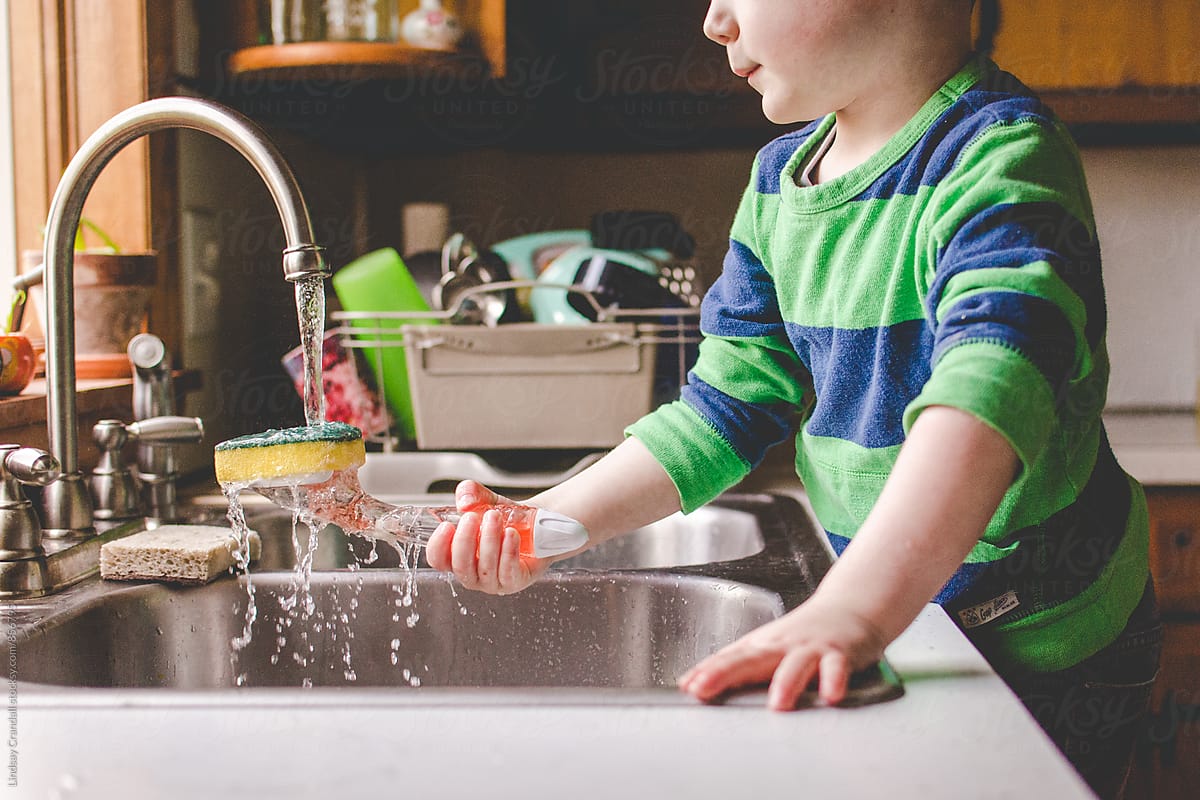 "Boy Playing With Dish Sponge At The Kitchen Sink" by Stocksy ...