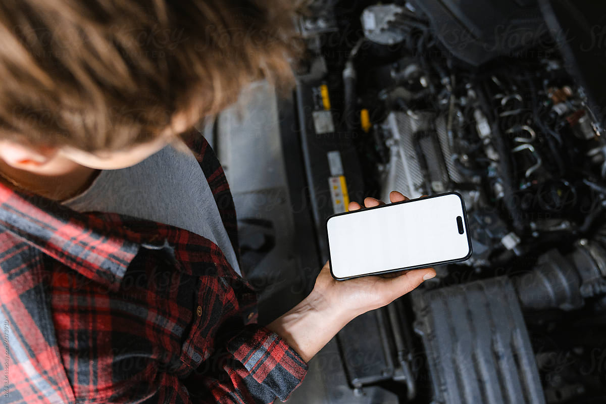 "A Man Uses A Mobile Phone With White Screen In A Car Repair Shop" by ...