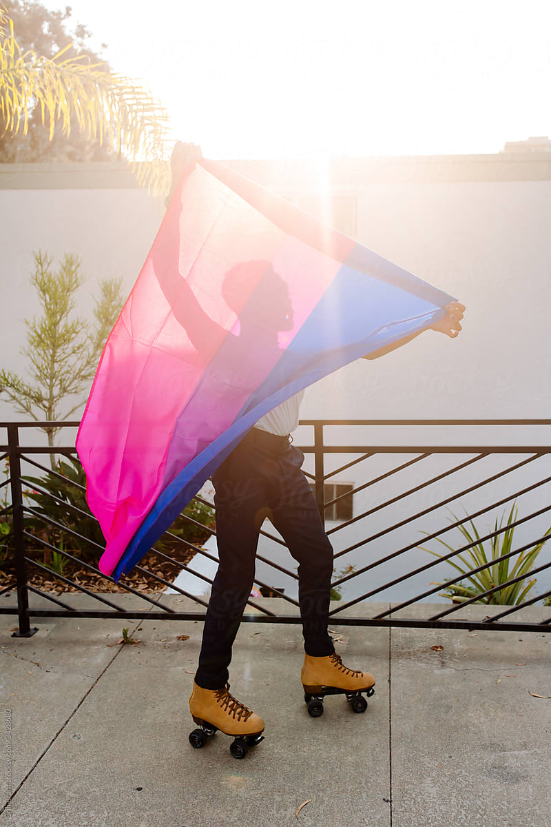 "Man On Rollerskates Behind Pride Flag" by Stocksy Contributor "Erin ...
