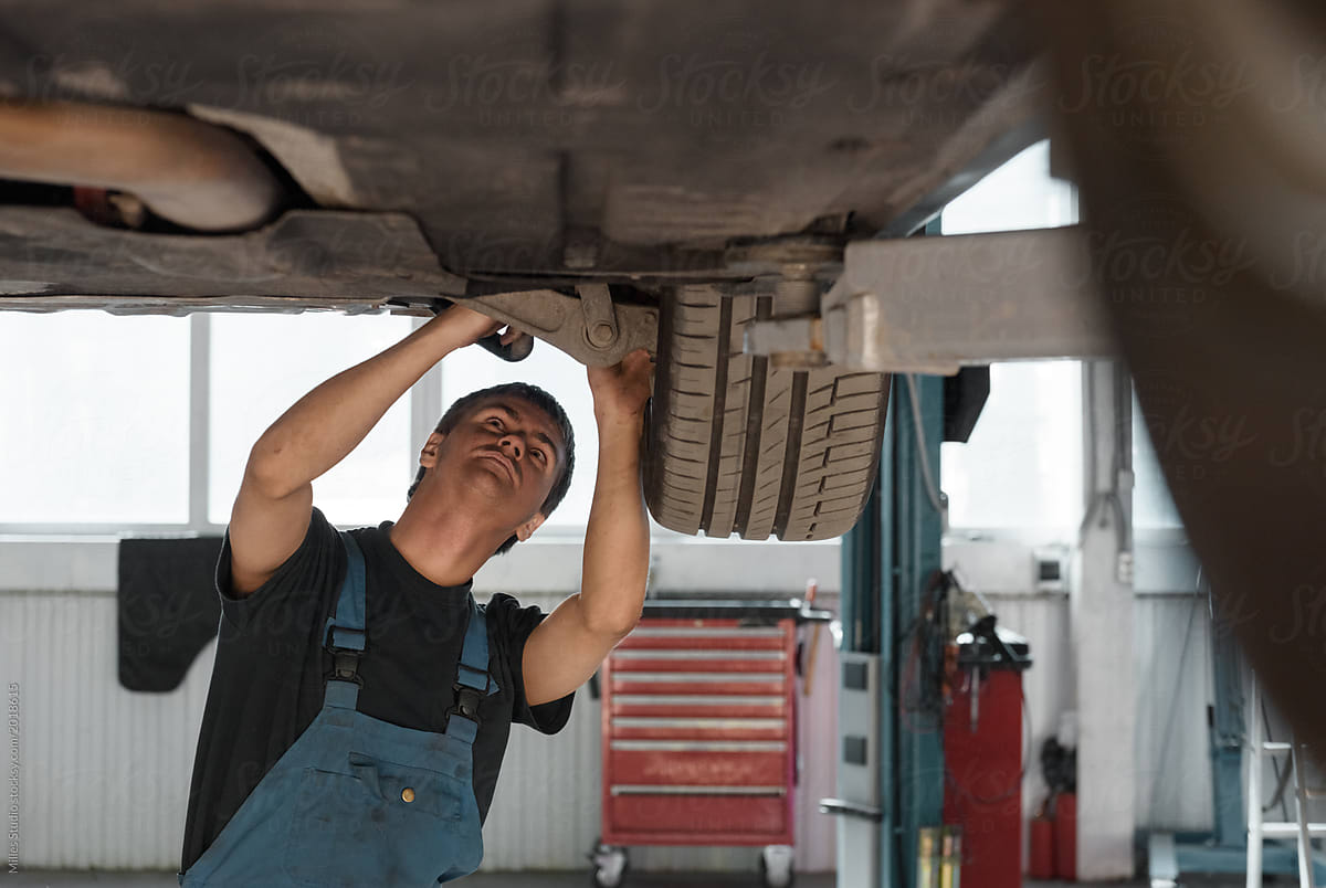 "Mechanic Exploring Car Bottom" by Stocksy Contributor "Milles Team ...