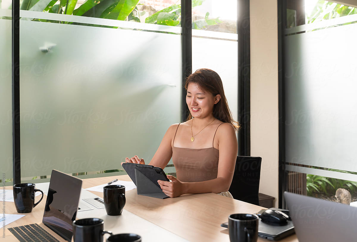 "Smiling Woman Using Tablet In Office Meeting Room" by Stocksy ...