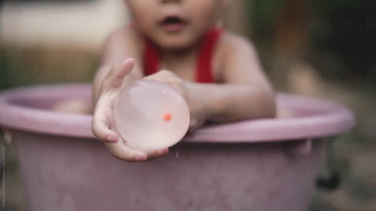 "Boy Squeezing Water Balloon" by Stocksy Contributor "Chalit Saphaphak ...