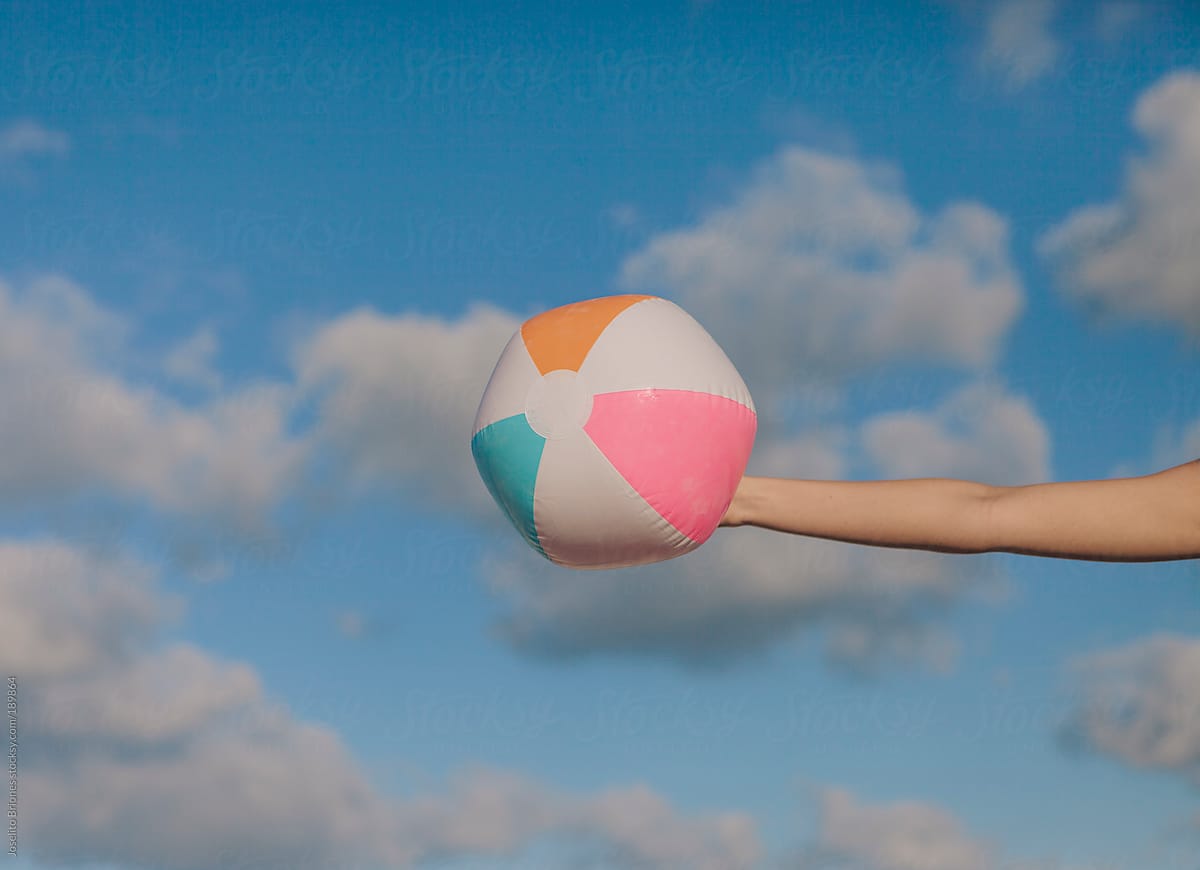 "Young Woman's Hand Holding Inflatable Beach Ball Against The Sky As ...