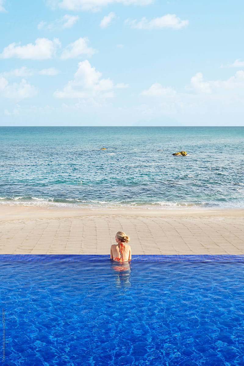 "Woman Looking At The Ocean From Infinity Pool At Luxury Resort" by ...